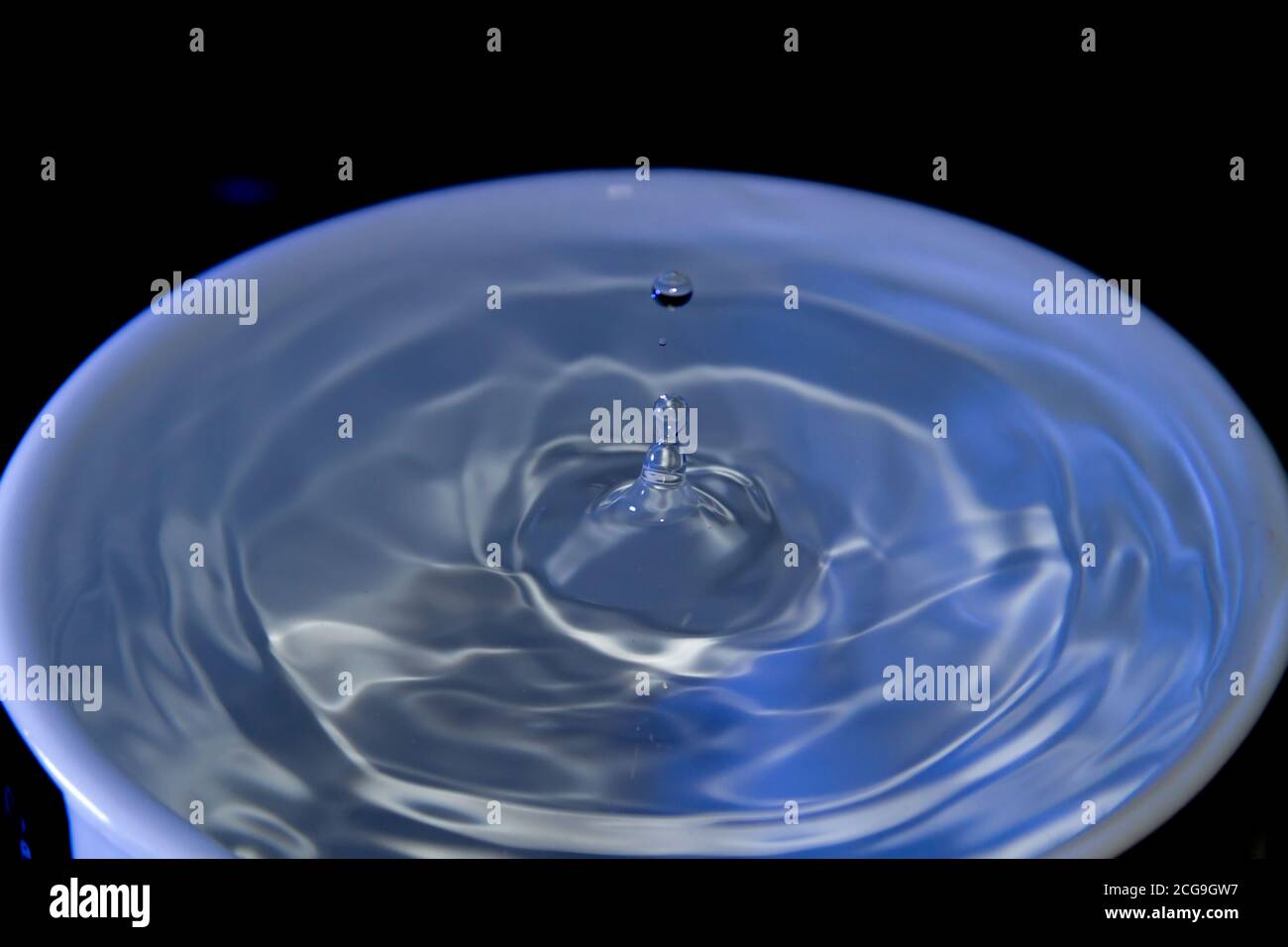 Water drop falling on a cup full with water Stock Photo - Alamy
