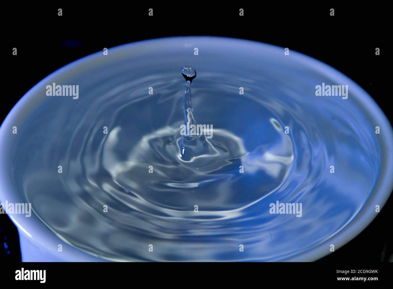 Water drop falling on a cup full with water Stock Photo - Alamy
