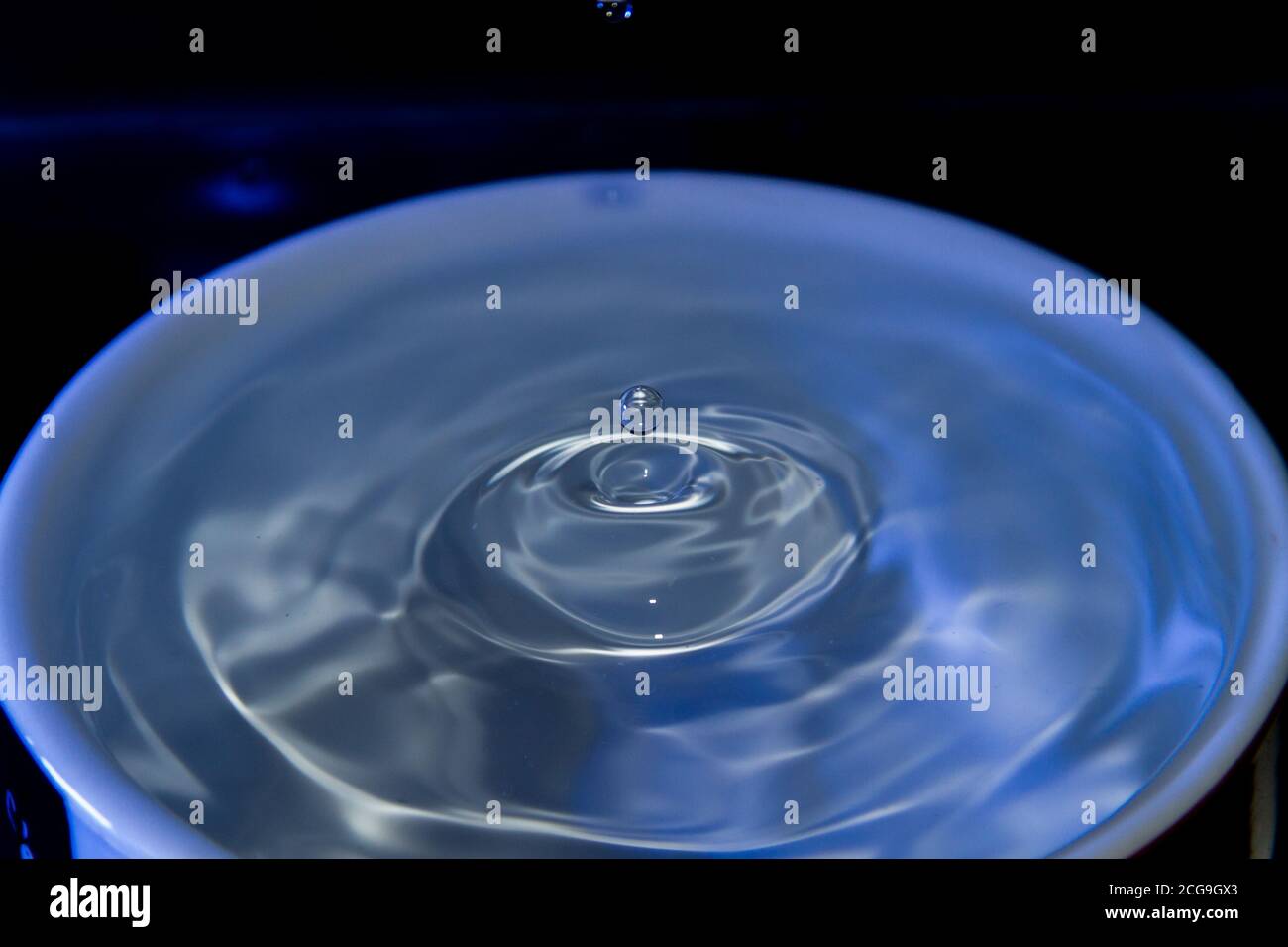 Water drop falling on a cup full with water Stock Photo - Alamy