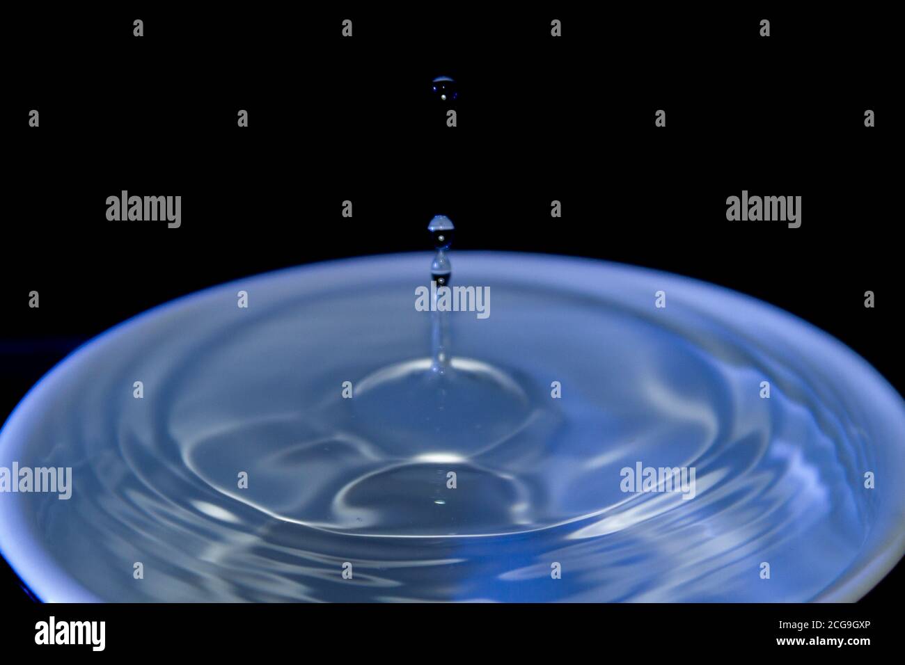 Water drop falling on a cup full with water Stock Photo - Alamy