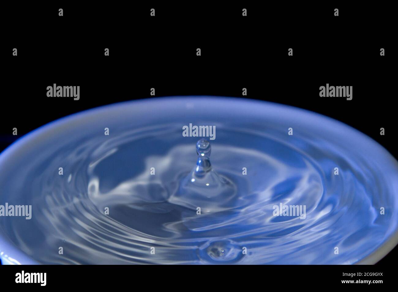 Water drop falling on a cup full with water Stock Photo - Alamy