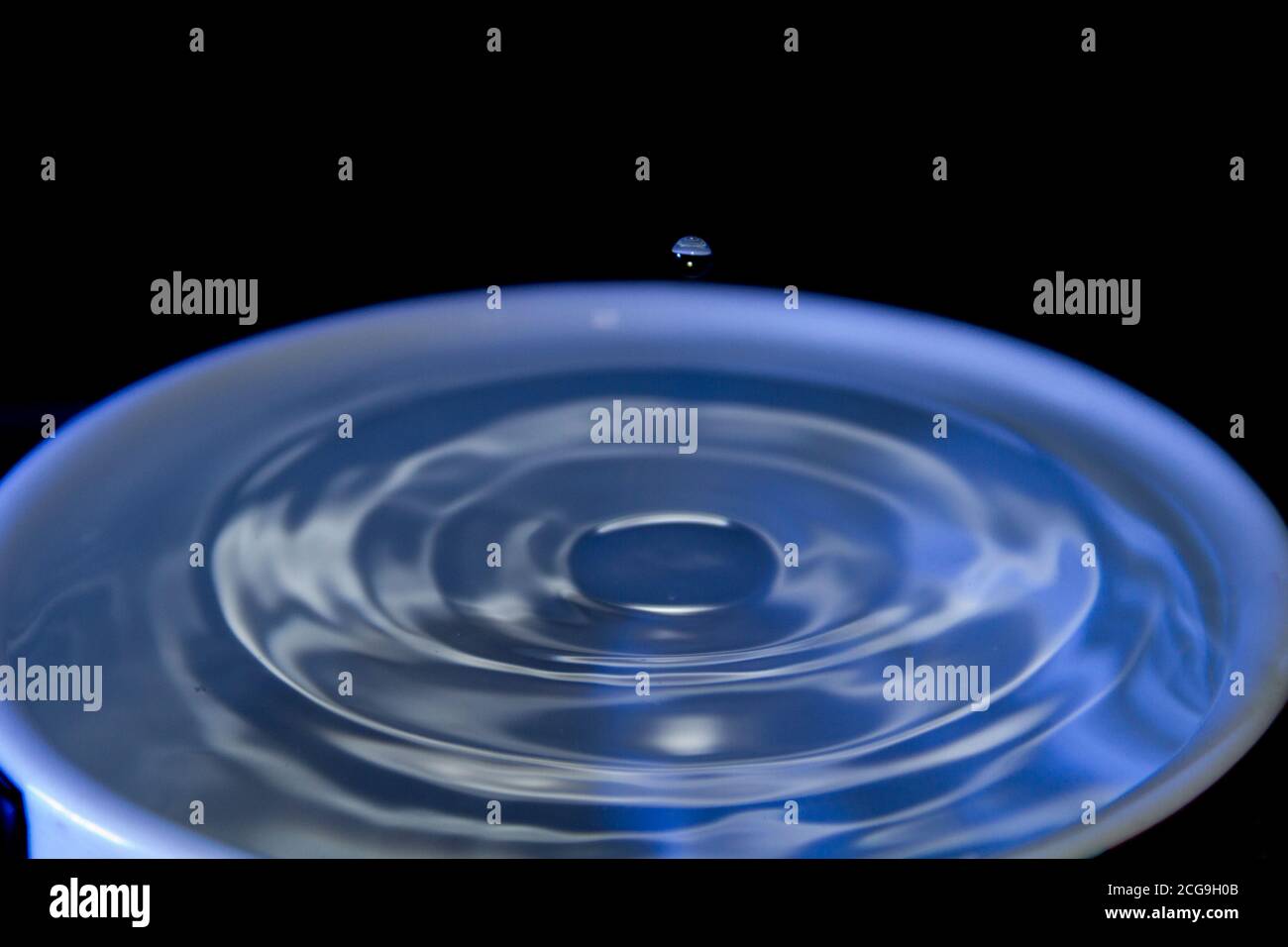 Water drop falling on a cup full with water Stock Photo - Alamy