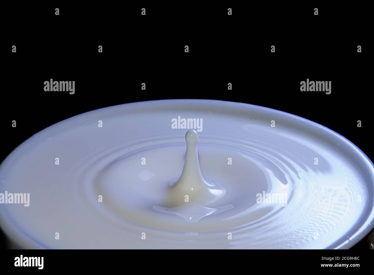 Milk drop falling on a cup full of milk Stock Photo - Alamy