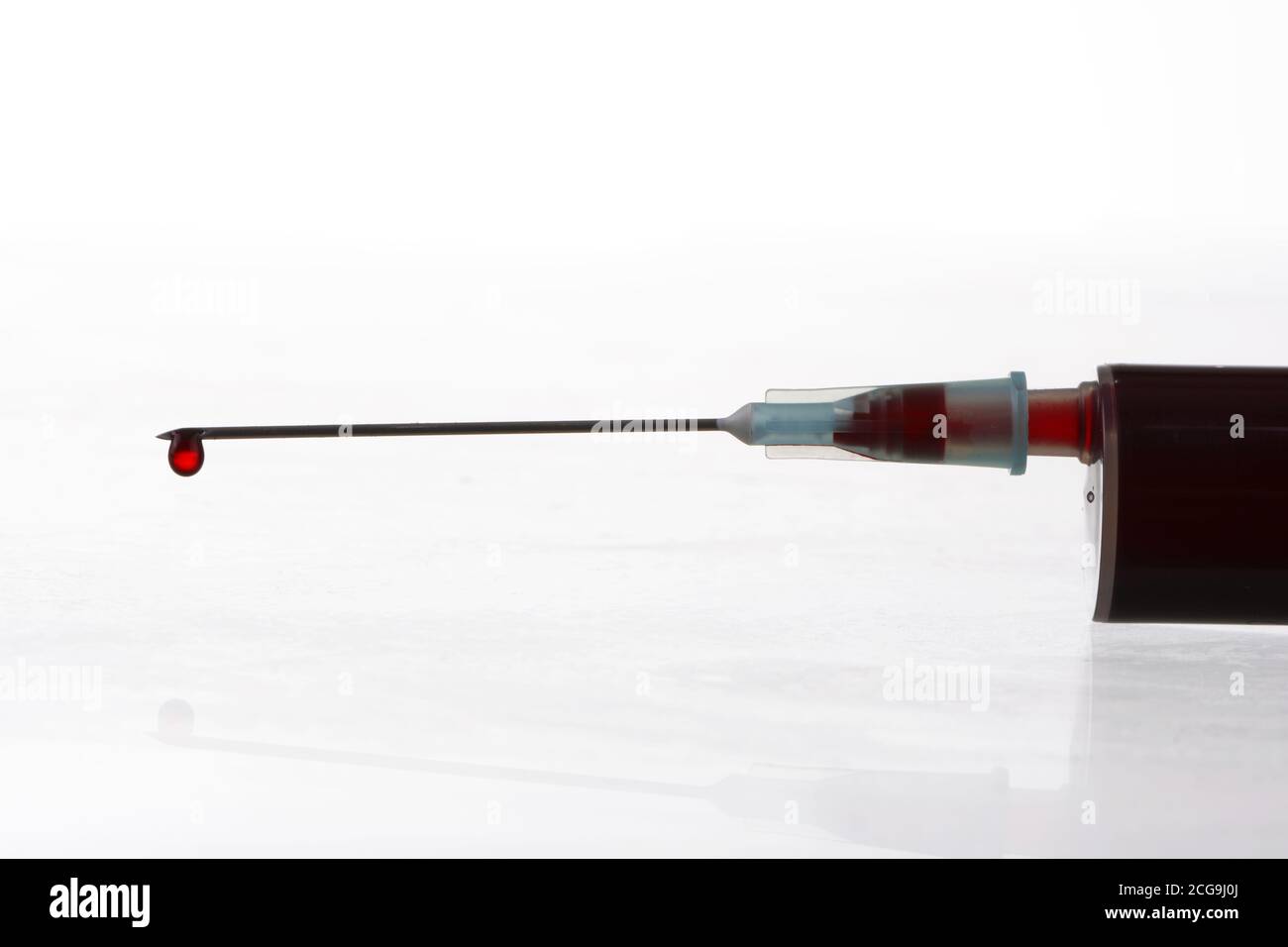 Macro view of drop of blood from syringe over white background. Blood ...