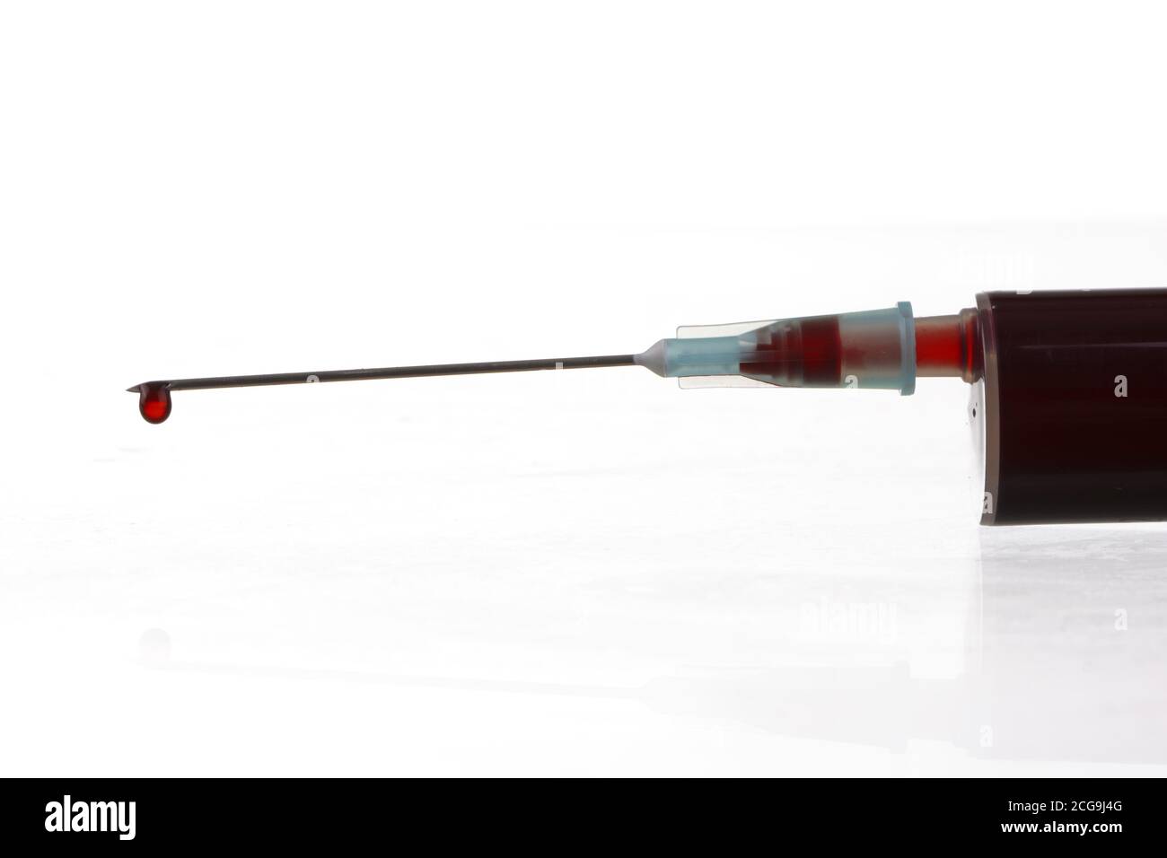 Macro view of drop of blood from syringe over white background. Blood ...