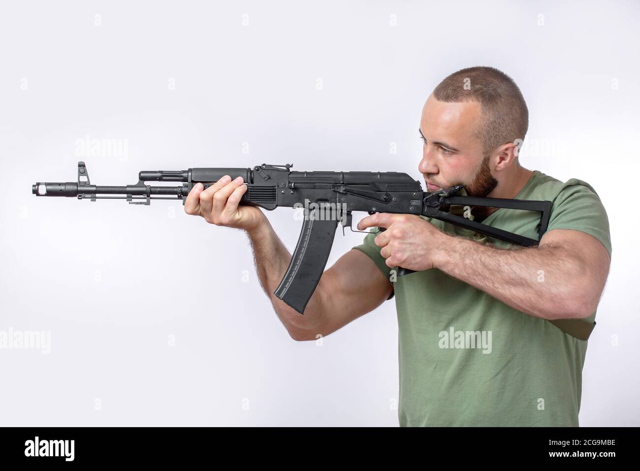 Strong caucasian shooter in casual clothing with sniper rifle standing ...