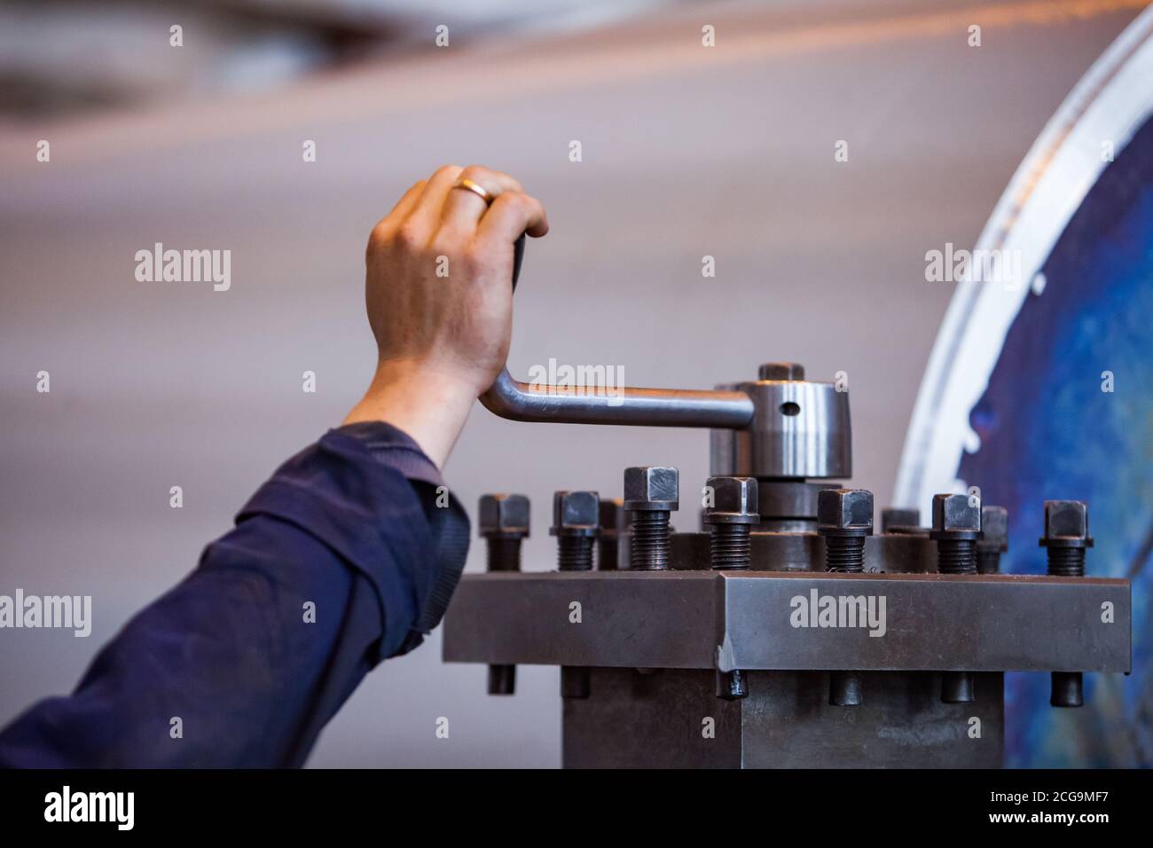 Worker's hand on lathe tool holder of metal turning machine. Low depth ...