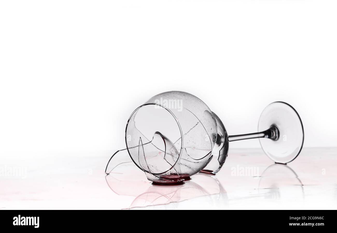 broken wine glass on a quilted table isolated on white background. red ...