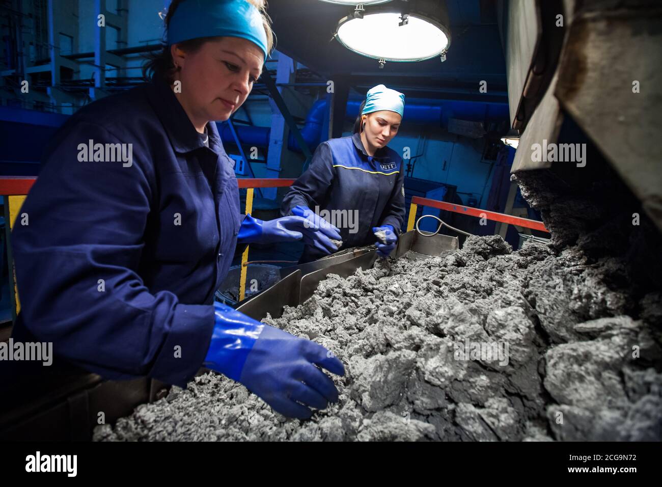 Titanium metallurgy plant. Two worker women in blue rubber work gloves ...