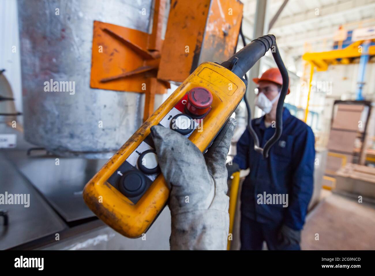 Two workers lifting up metallurgical bucket with metal titanium sponge ...