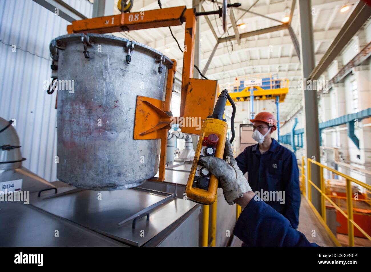 Workers lifting up metallurgical bucket with metal titanium sponge ...