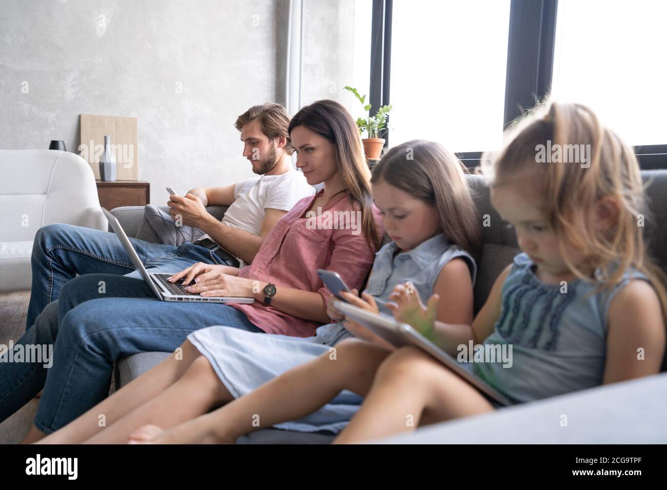 Modern family values. Father, mother and daughters using electronic ...