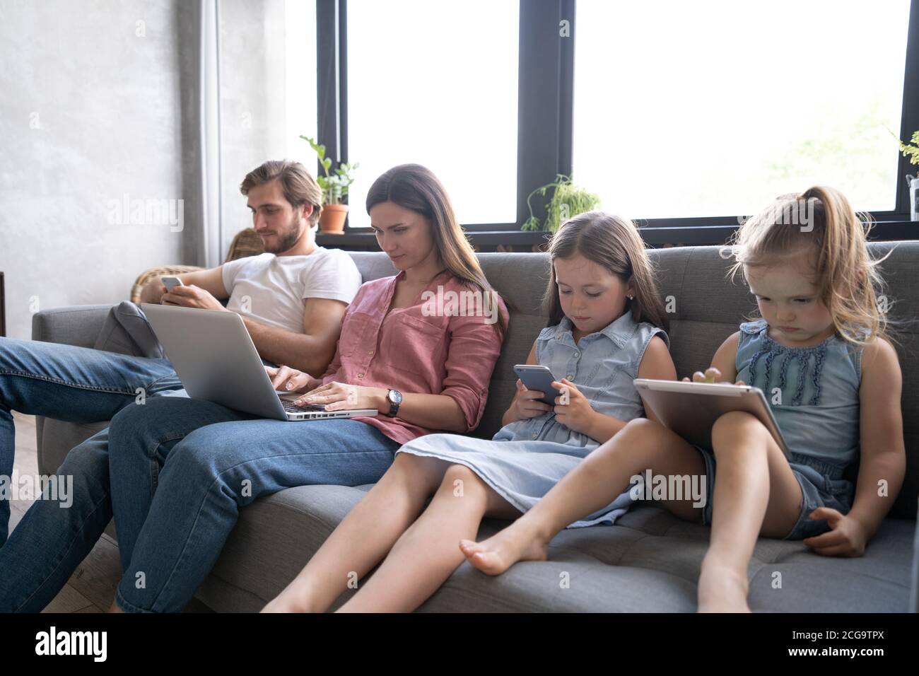 Modern family values. Father, mother and daughters using electronic ...