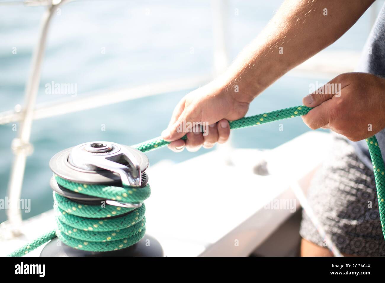 Male hands close up doing sailor job with yacht tackle during the ocean ...