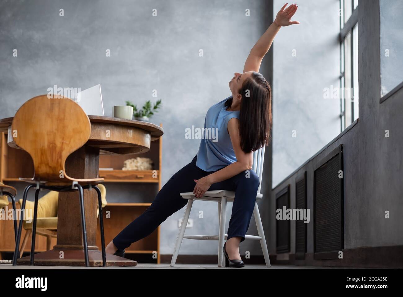 Woman practicing yoga using chair, stretching in Extended Side Angle ...