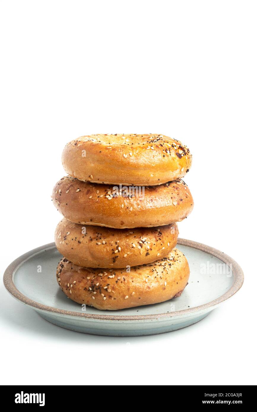 A single tall stack of four freshly baked bagels on a ceramic plate set ...