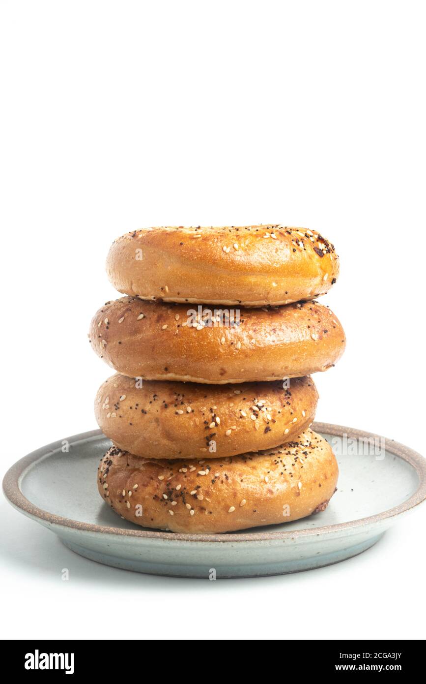 A single tall stack of four freshly baked bagels on a ceramic plate set ...