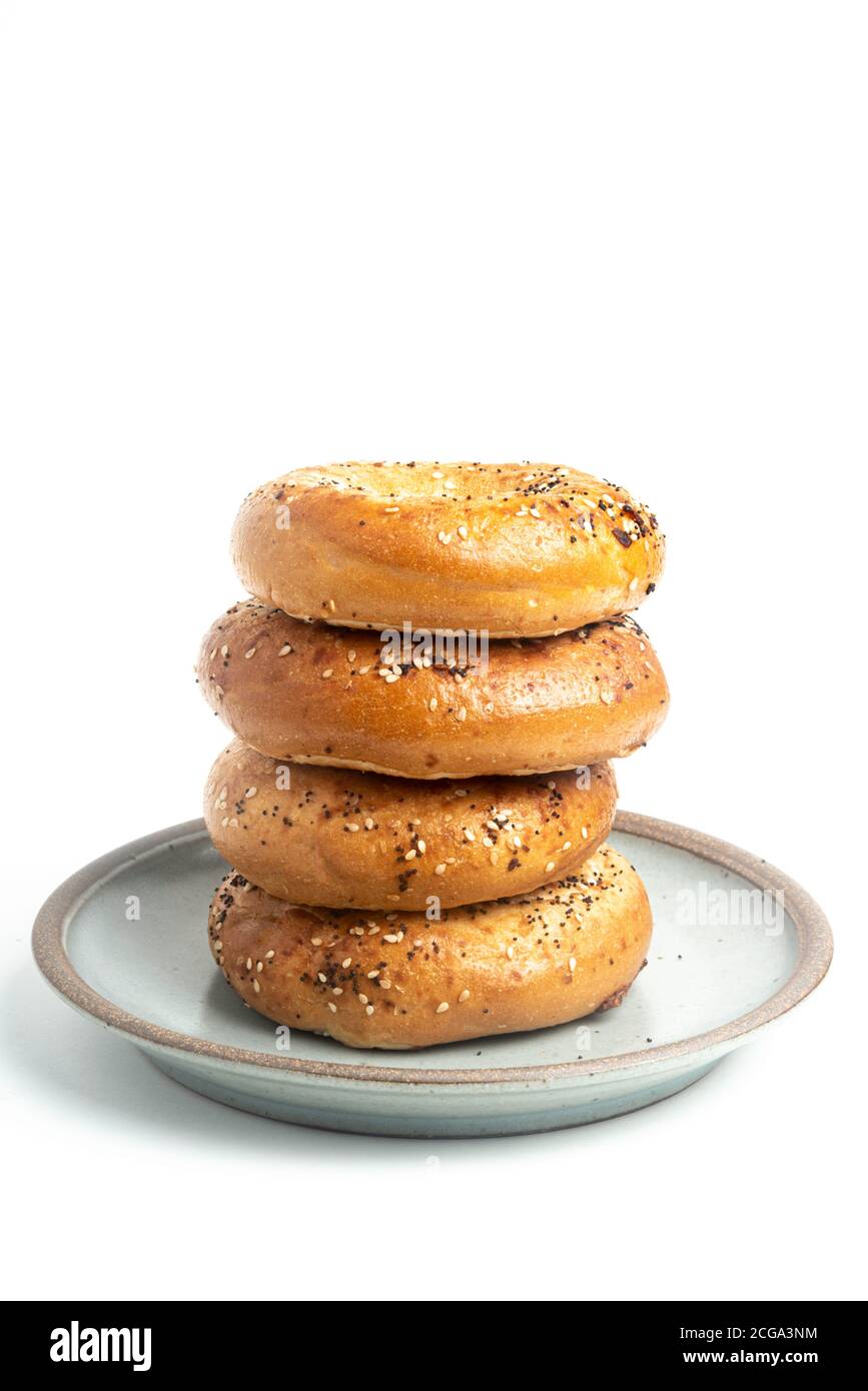 A single tall stack of four freshly baked bagels on a ceramic plate set ...