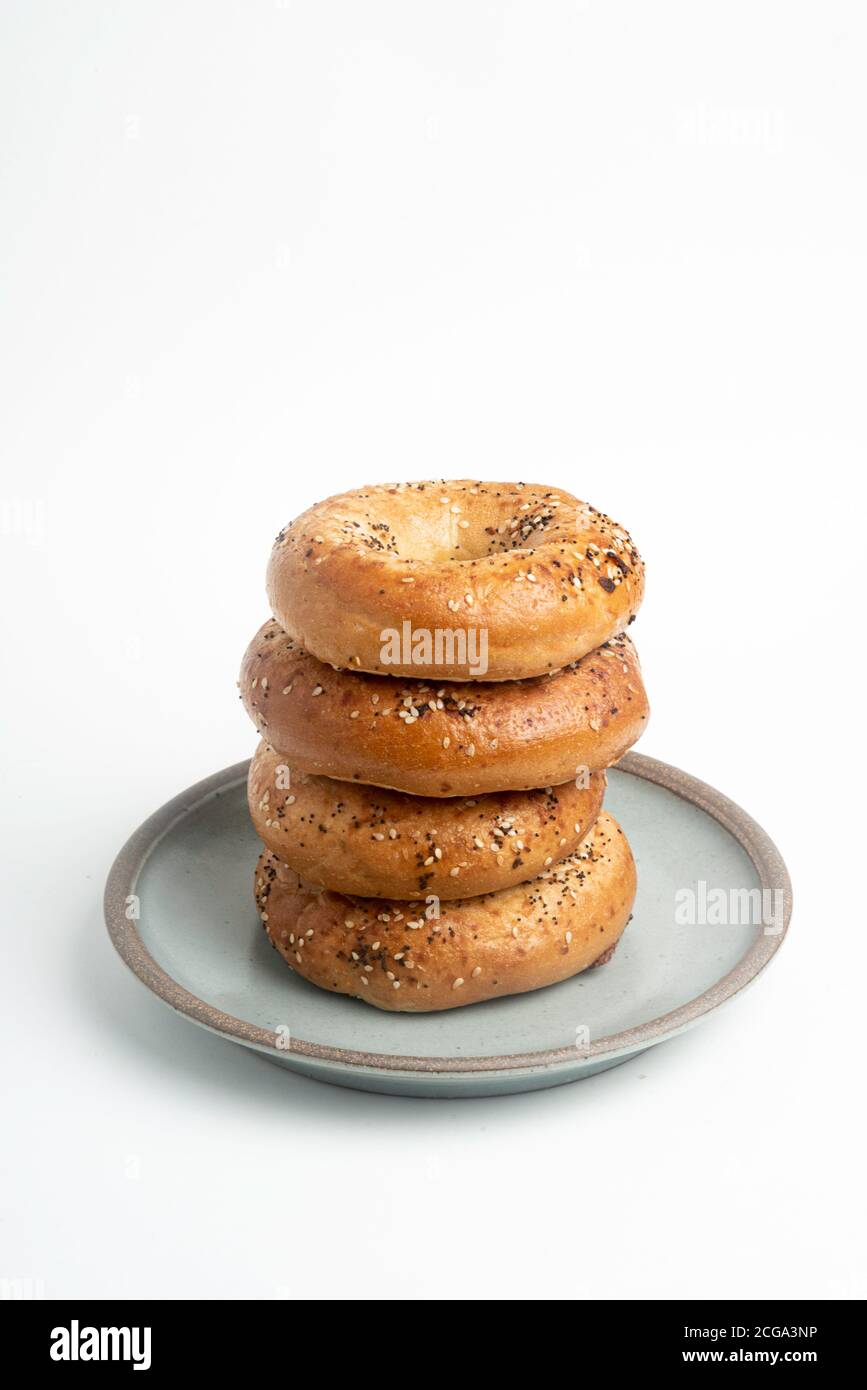 A single tall stack of four freshly baked bagels on a ceramic plate set ...
