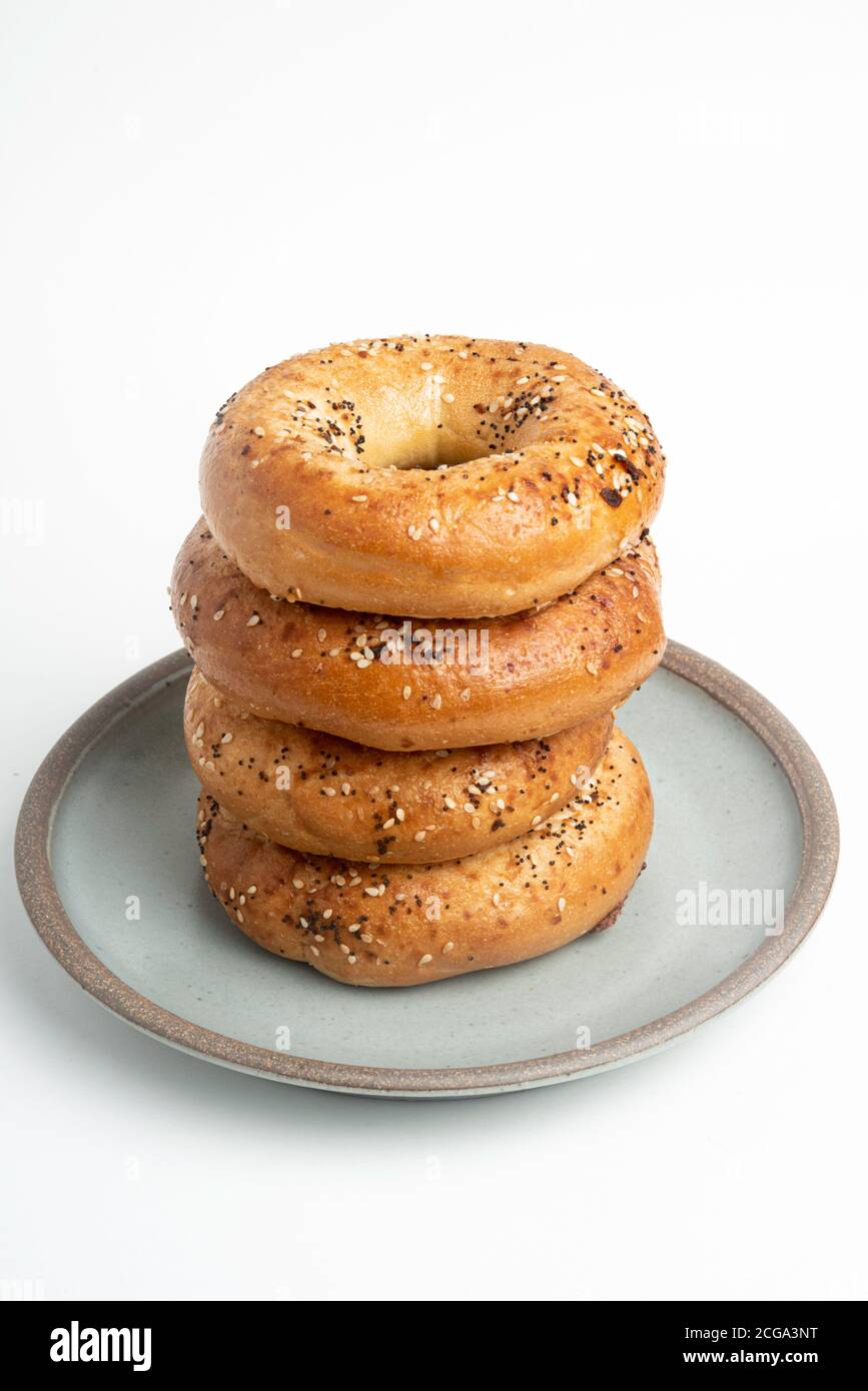 A single tall stack of four freshly baked bagels on a ceramic plate set ...