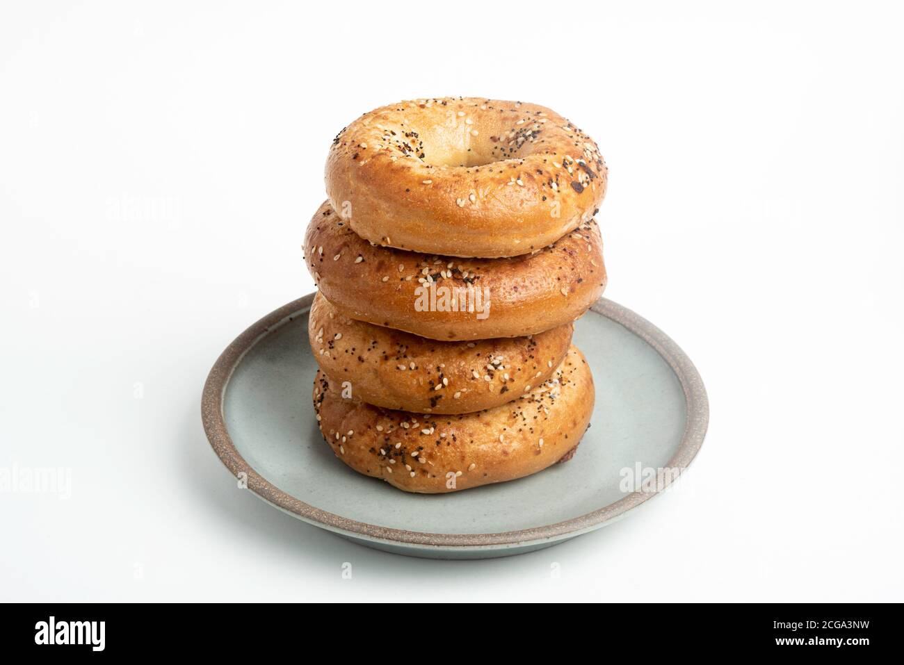 A single tall stack of four freshly baked bagels on a ceramic plate set ...