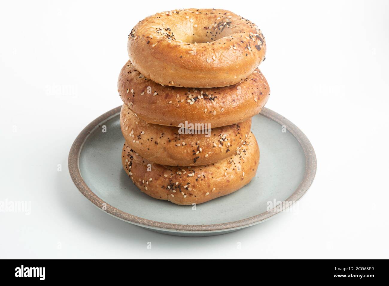 A single tall stack of four freshly baked bagels on a ceramic plate set ...
