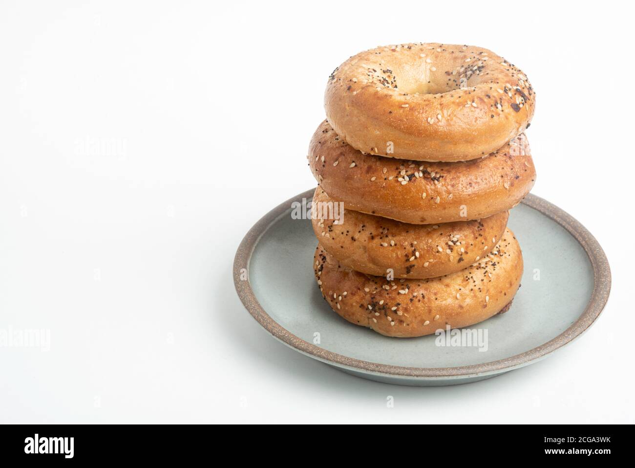 A single tall stack of four freshly baked bagels on a ceramic plate set ...