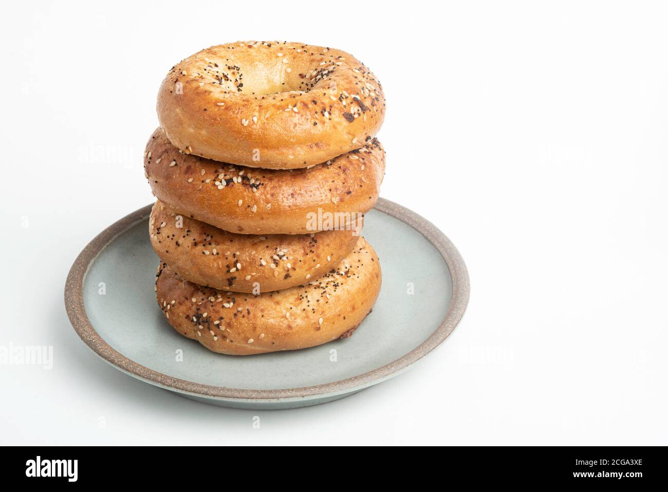 A single tall stack of four freshly baked bagels on a ceramic plate set ...