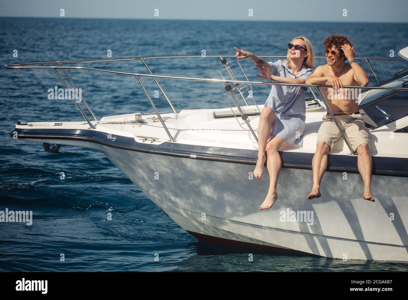 Young european romantic couple smiling at camera while sitting at bow ...