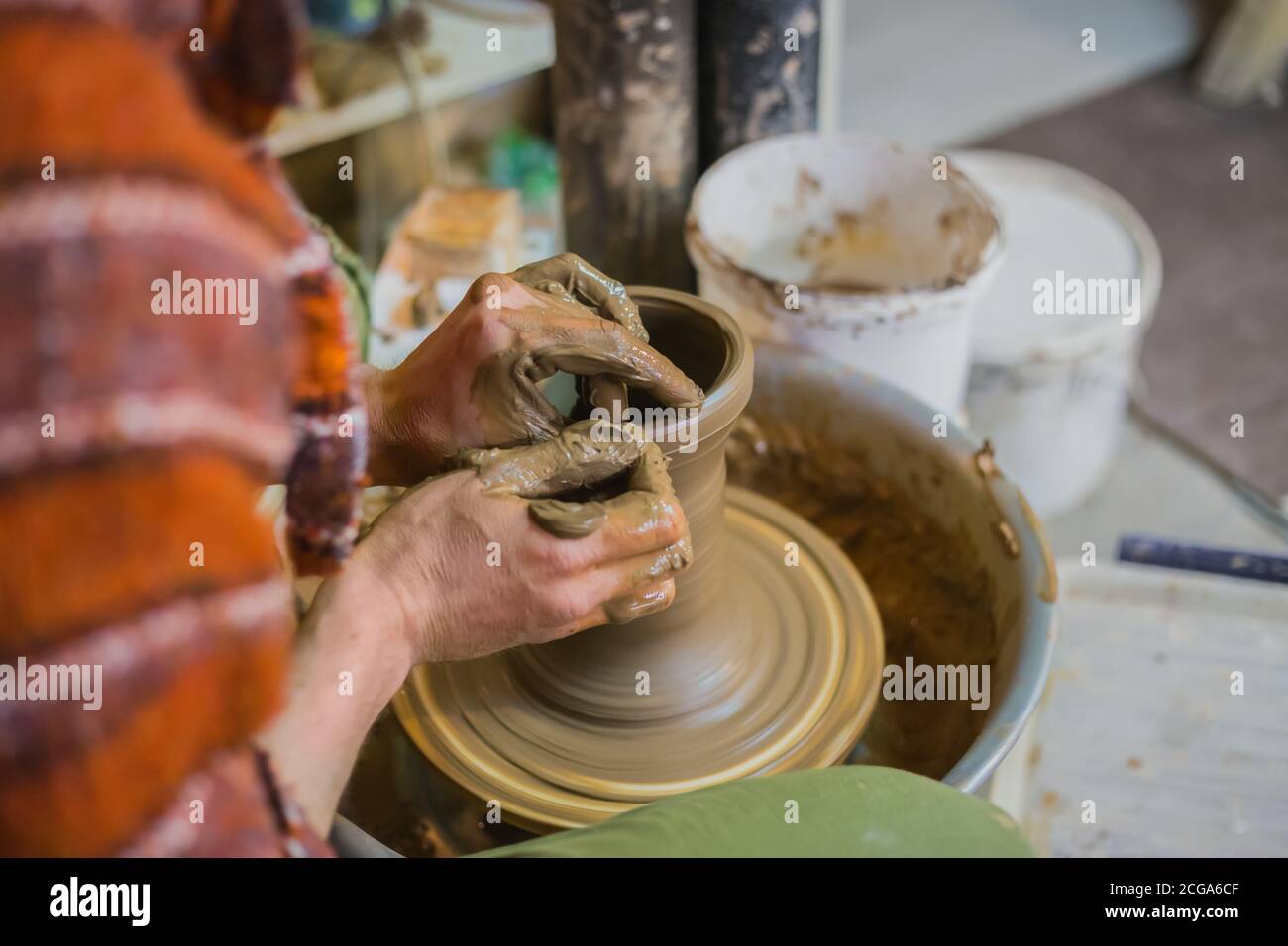 Professional male potter making pot on pottery wheel at workshop ...