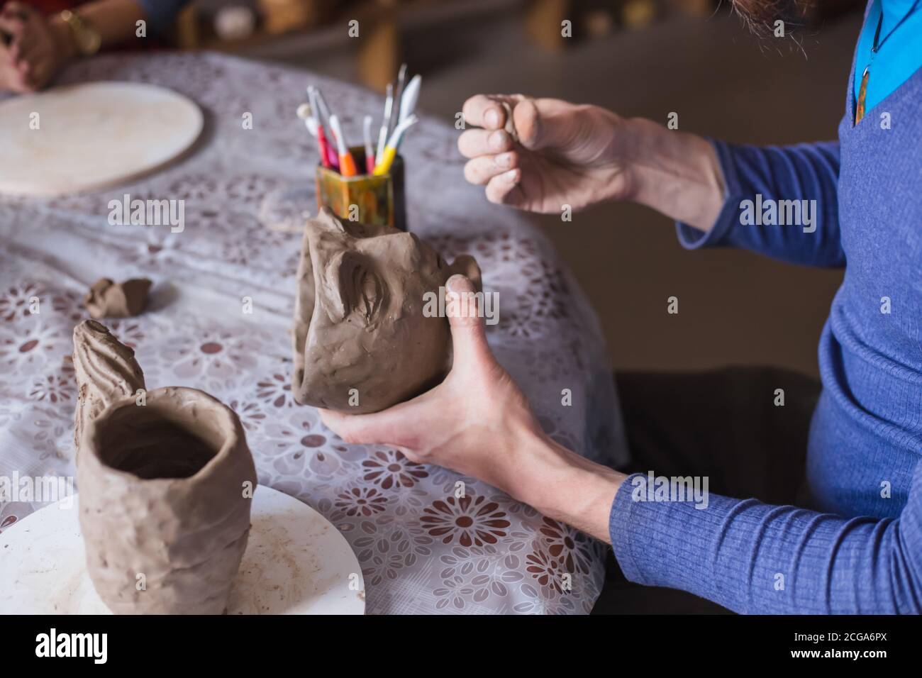 Professional male potter shaping mug in shape of human face with ...