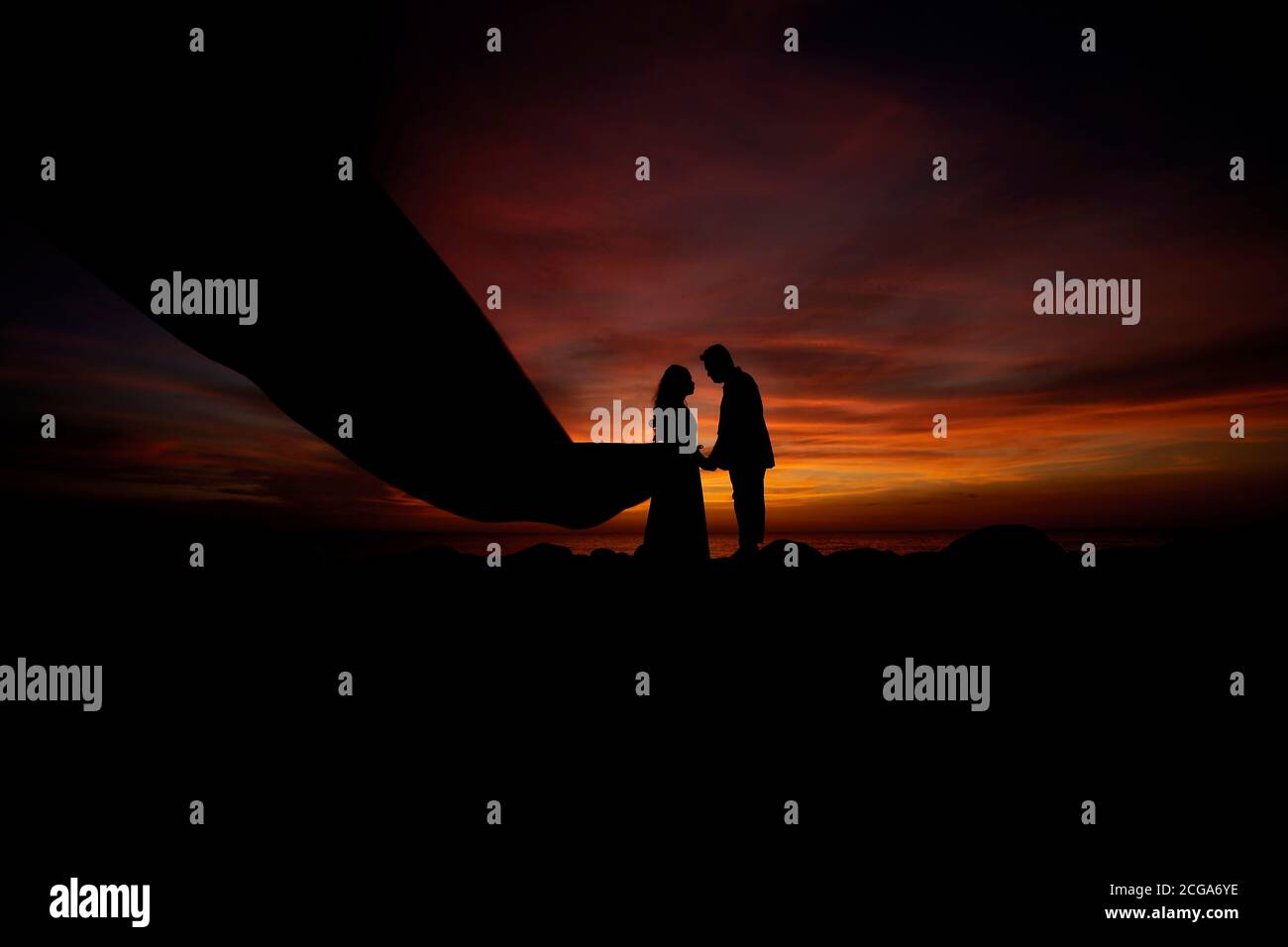 Couple man and woman hold hands on sunset background Stock Photo - Alamy
