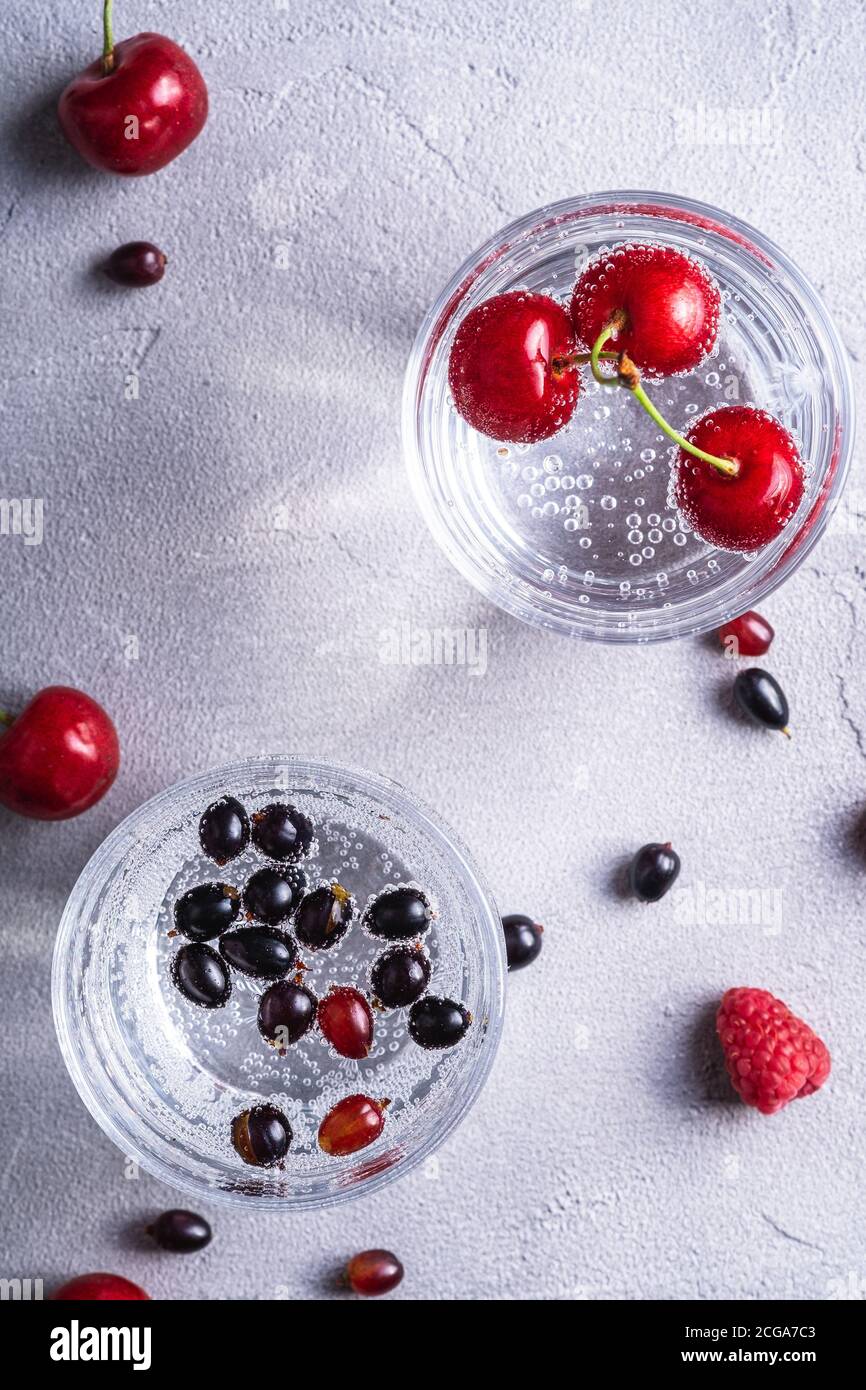 Fresh cold sparkling water drink with berries in two transparent glass ...