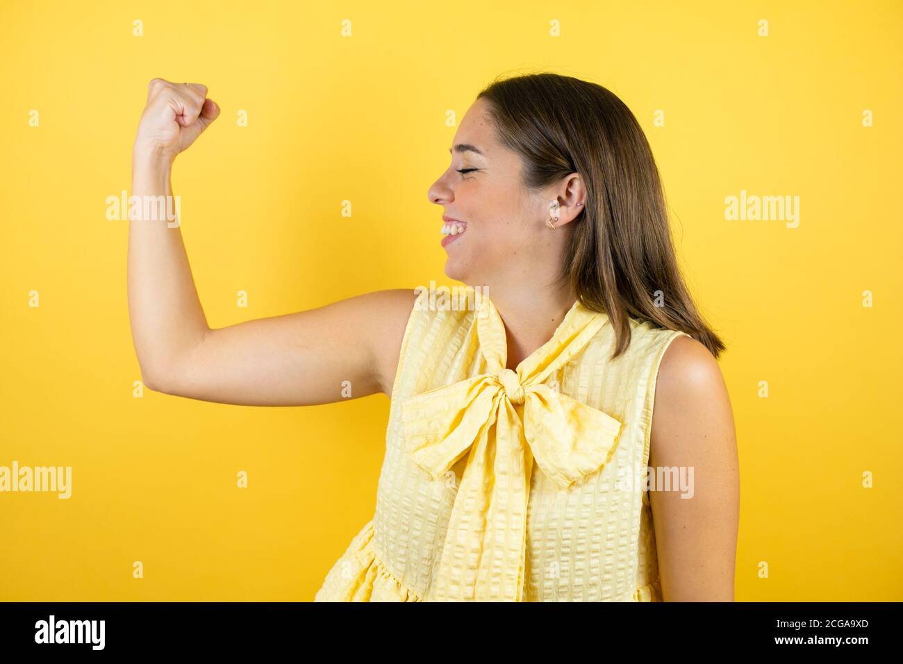 Young beautiful woman over isolated yellow background showing arms ...