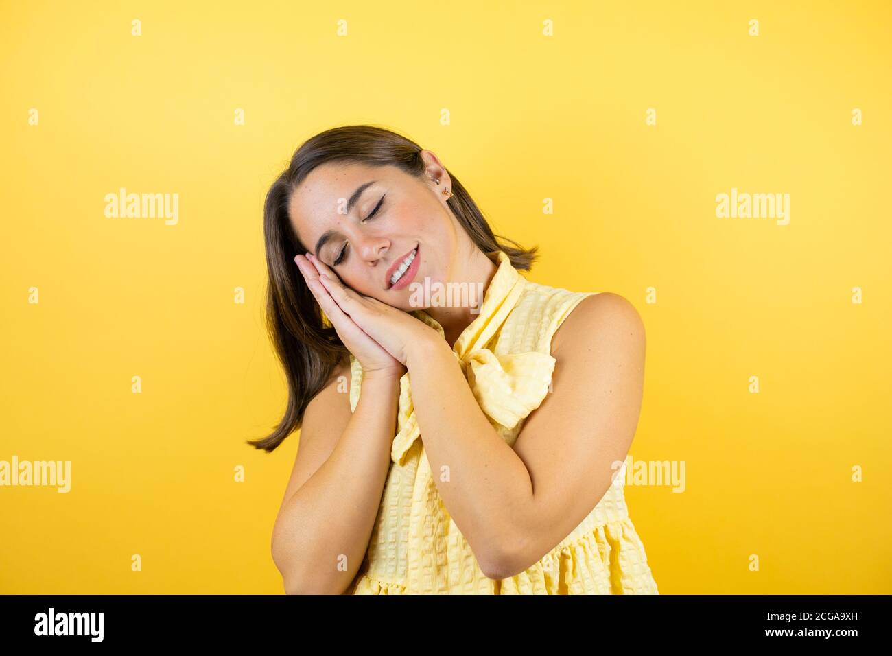 Young beautiful woman over isolated yellow background sleeping tired ...