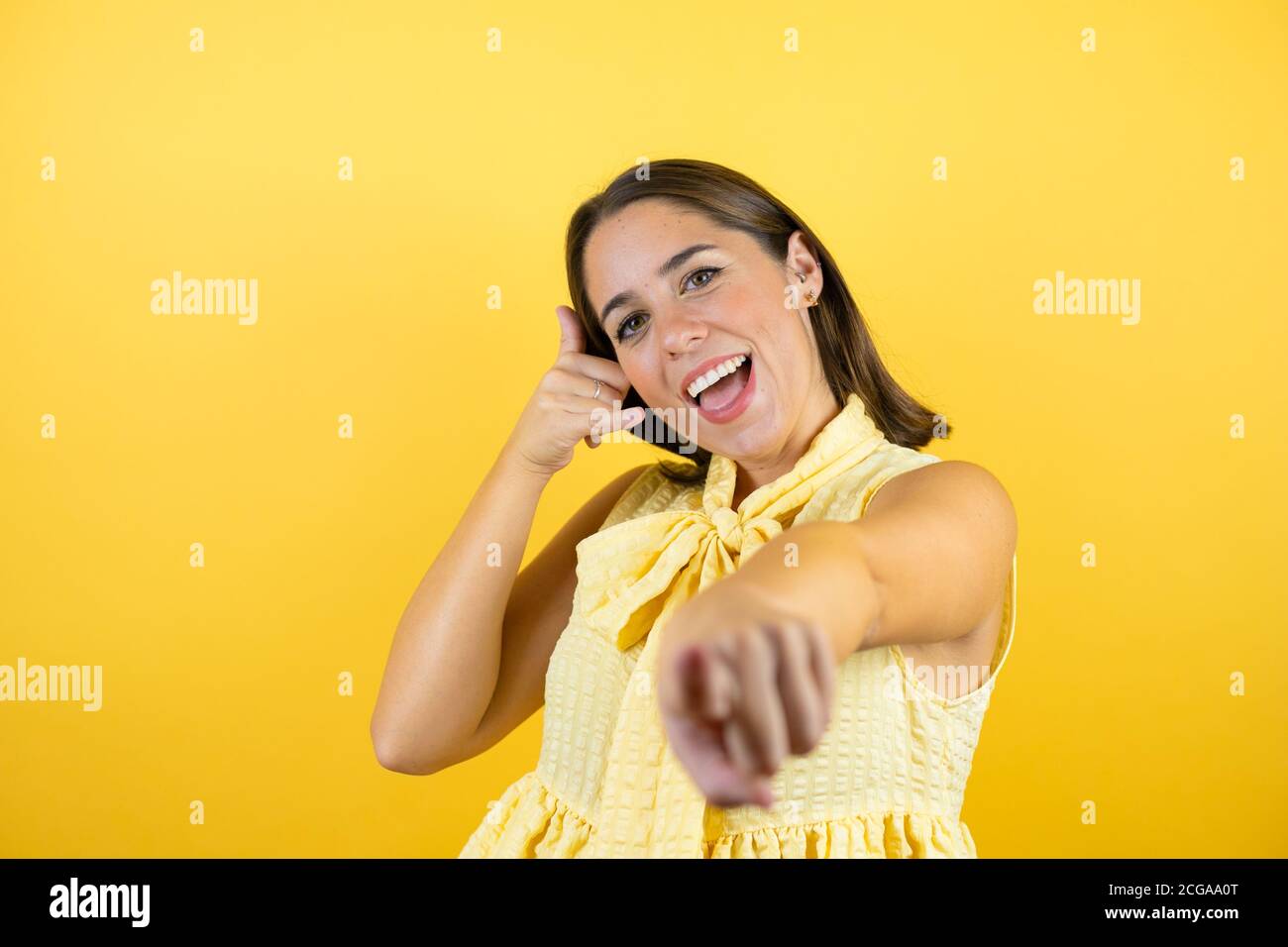 Young beautiful woman over isolated yellow background doing the “call ...