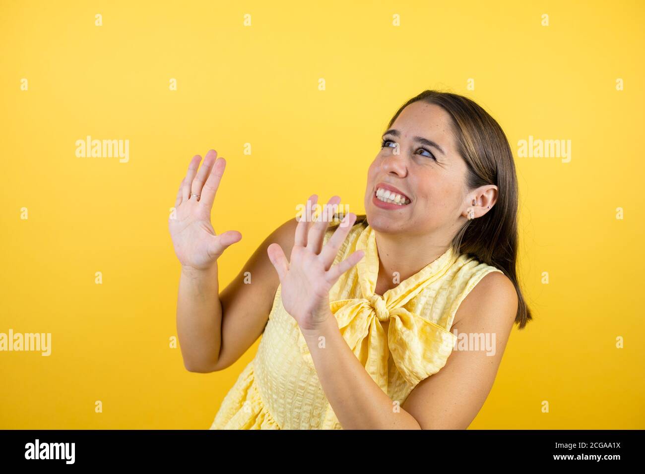 Young beautiful woman over isolated yellow background scared with her ...