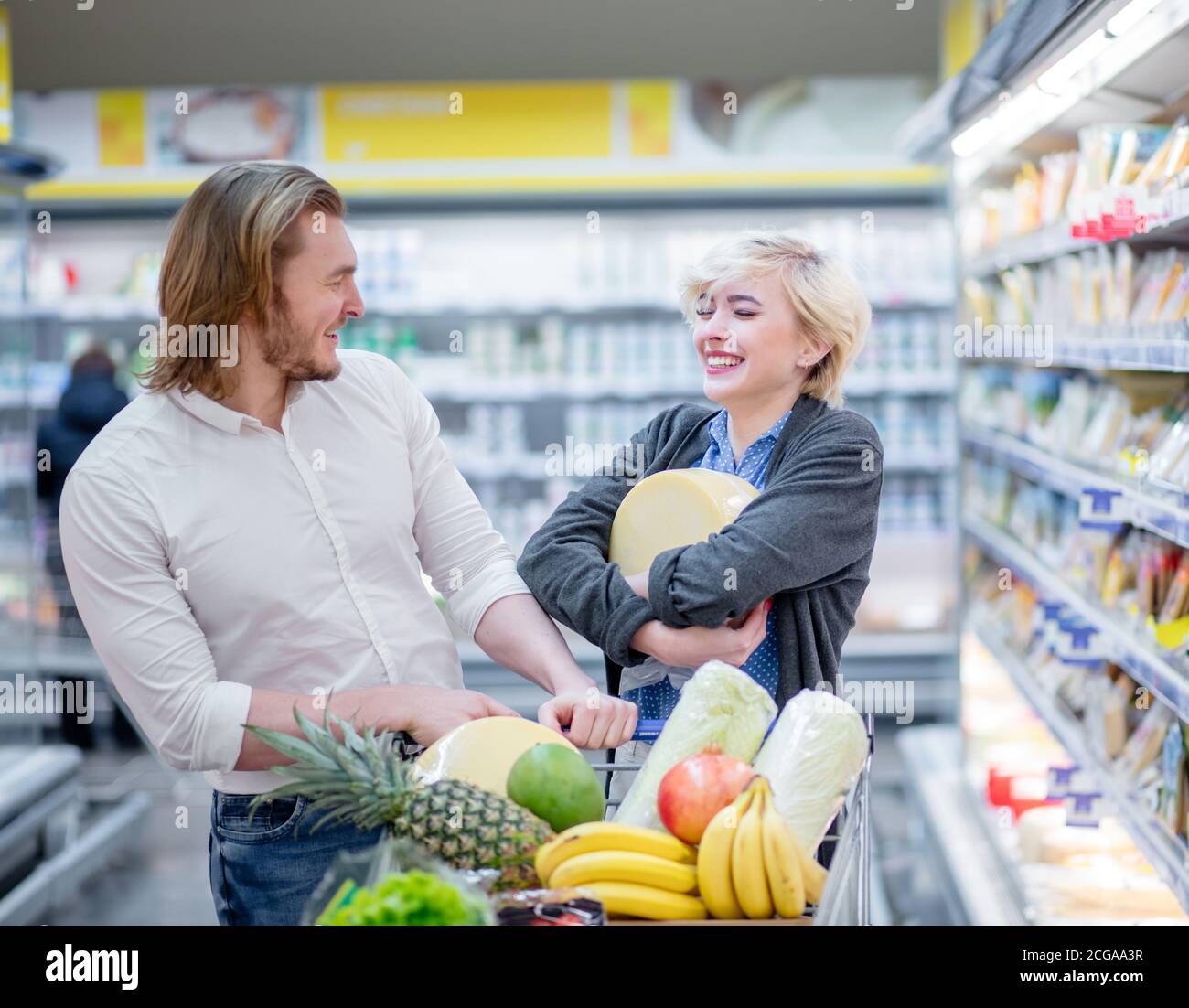 Caucasian cheerful male and female shoppers with grocery products cart ...