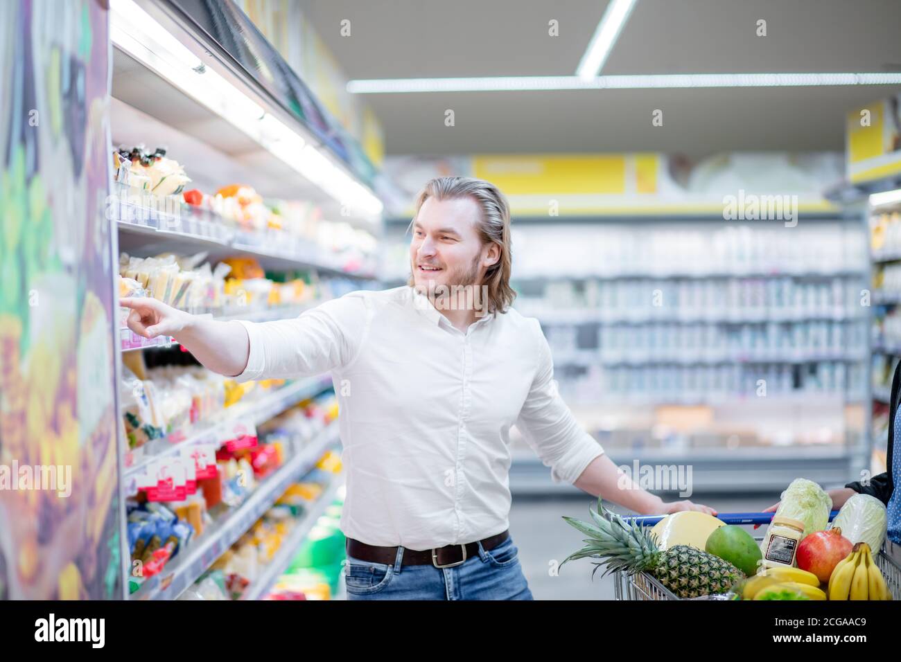 Cheerful positive young man with food cart making fun in the grocery ...