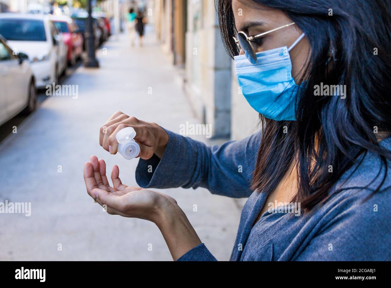 Girl disinfecting her hands with hand sanitizer and wearing a mask to ...