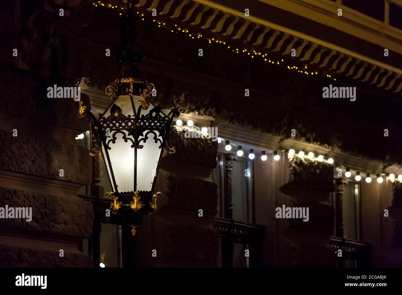 black wrought iron lantern with frosted glass shines on facade of ...