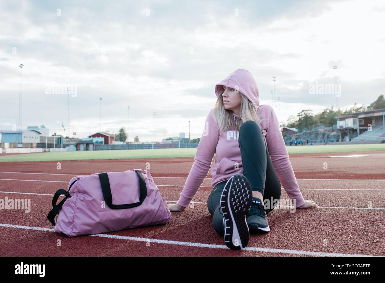 woman sat on a running track looking thoughtful Stock Photo - Alamy