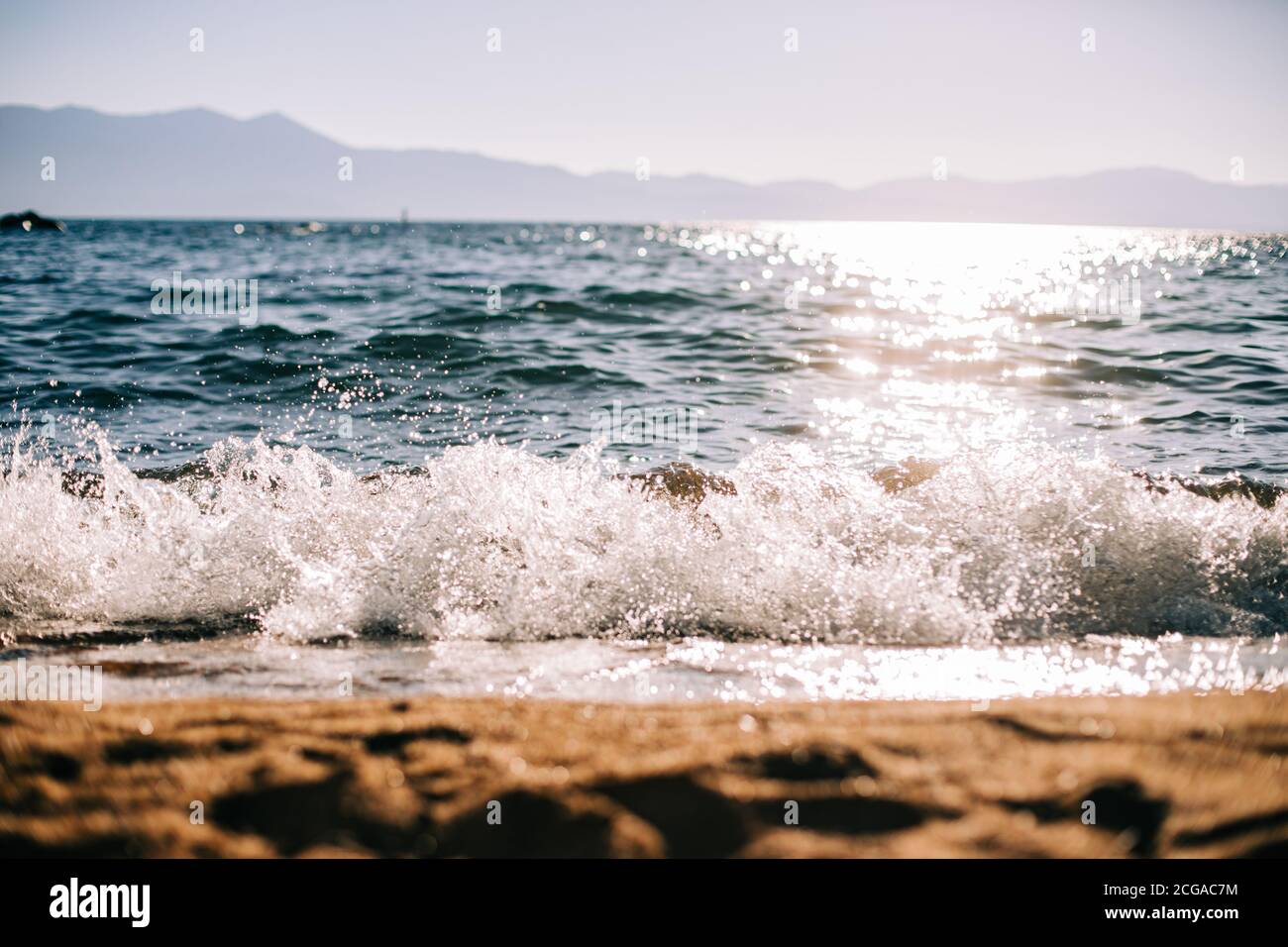 Splashing Wave on Sandy Shore with Sparkling Sunshine on Water Stock ...