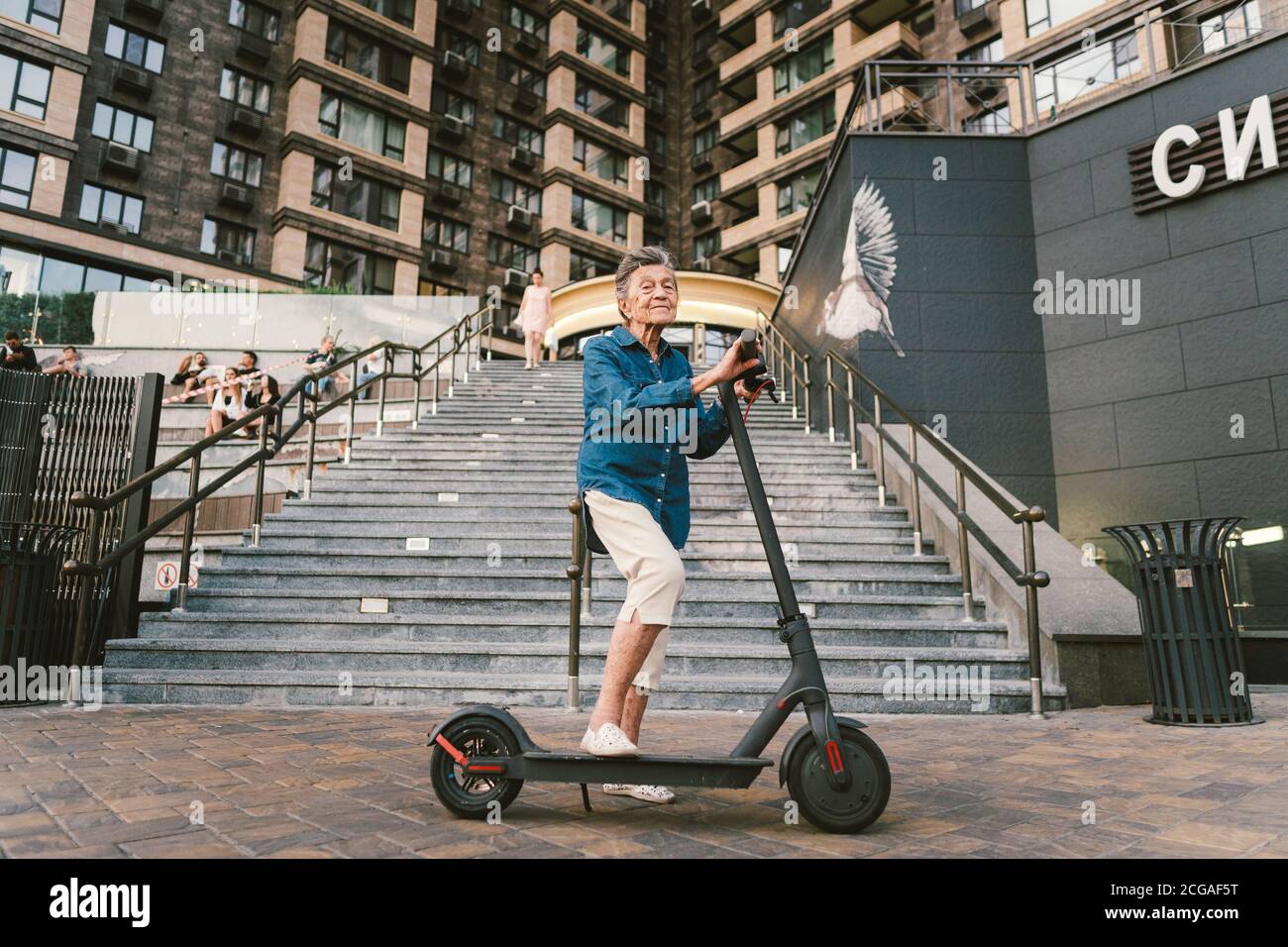 Cheerful elderly woman on a scooter. Grandma rides a scooter ...