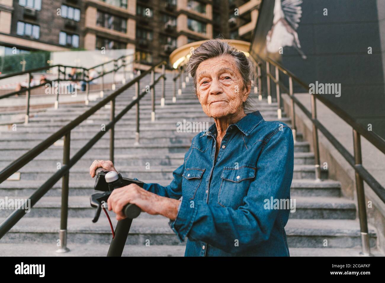 Old woman near scooter. Grandmother progressive woman. Senior having ...