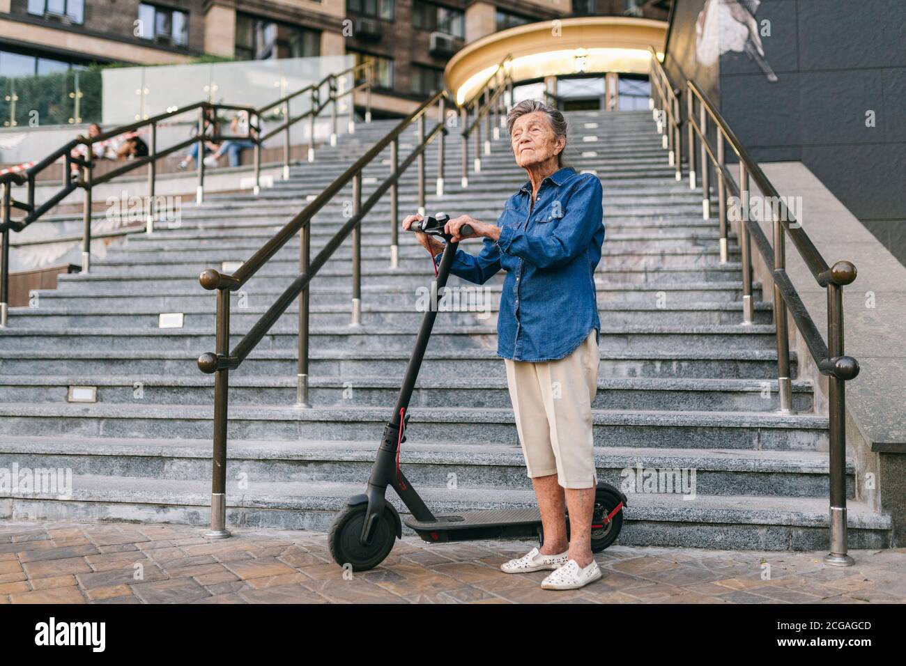 Active old woman riding electric scooter. Retired lady uses ...