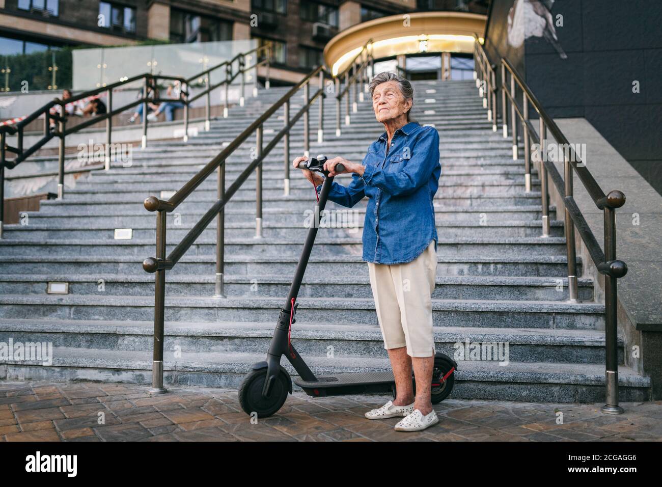 Cheerful elderly woman on a scooter. Grandma rides a scooter ...