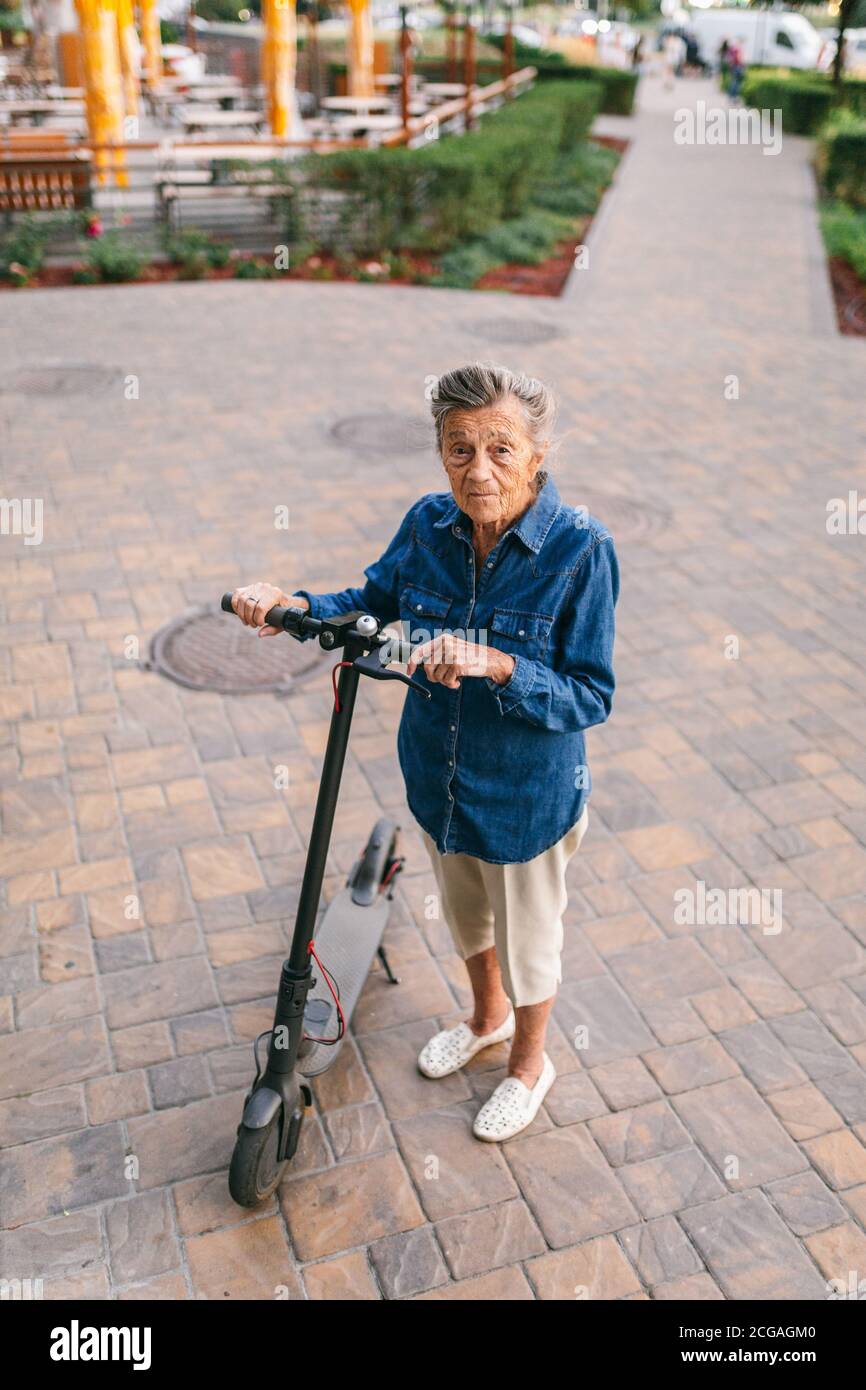 Active old woman riding electric scooter. Retired lady uses ...
