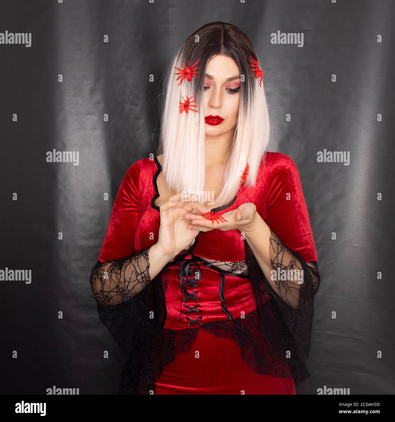 Young beautiful blonde woman in a red vampire dress on a black ...