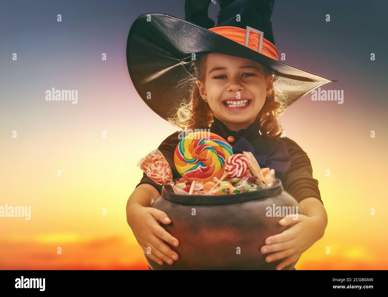 Happy Halloween! Cute little witch with candy. Child girl outdoors ...